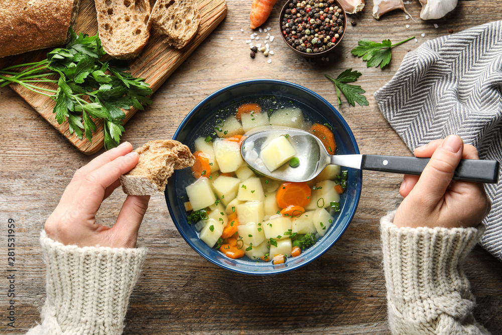 Woman eating fresh homemade vegetable soup at wooden table, top view ...