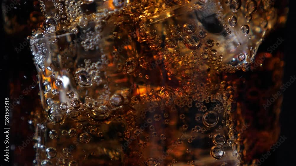 Pouring coca cola into the glass. Closeup on black background. Slow ...
