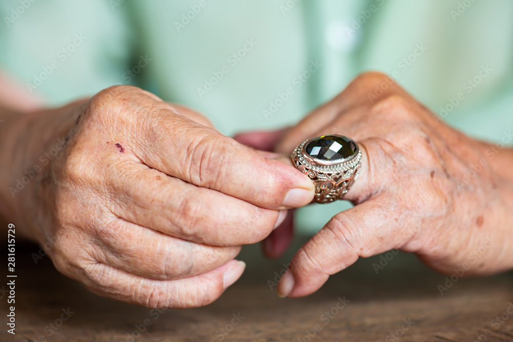 Senior man is wearing jewellery ring in left ring finger, on wooden ...