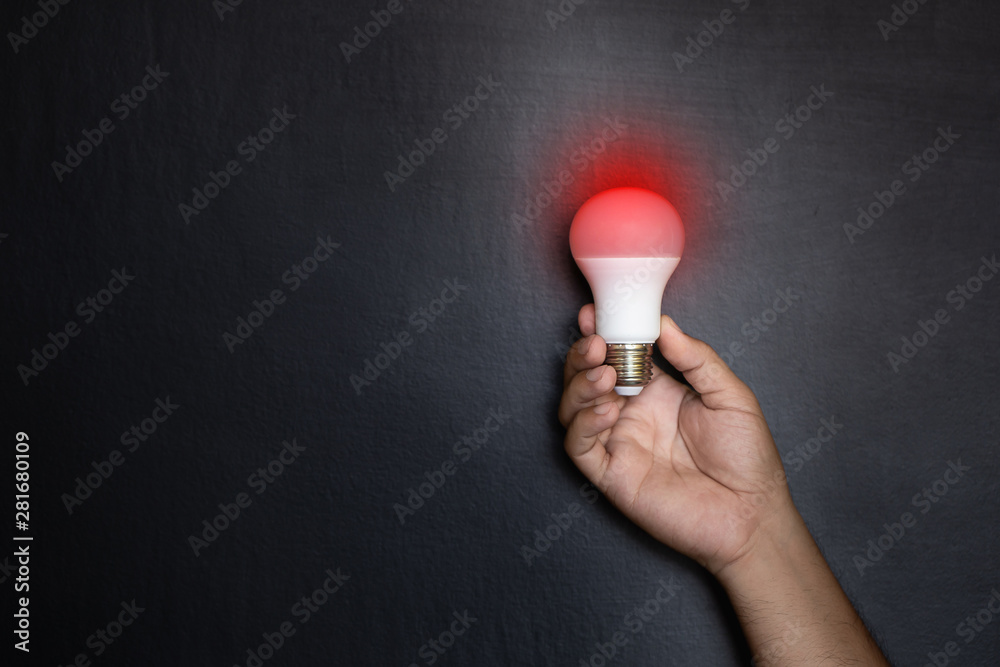 Bulb in hand, red light on black background Concept concept symbol ...