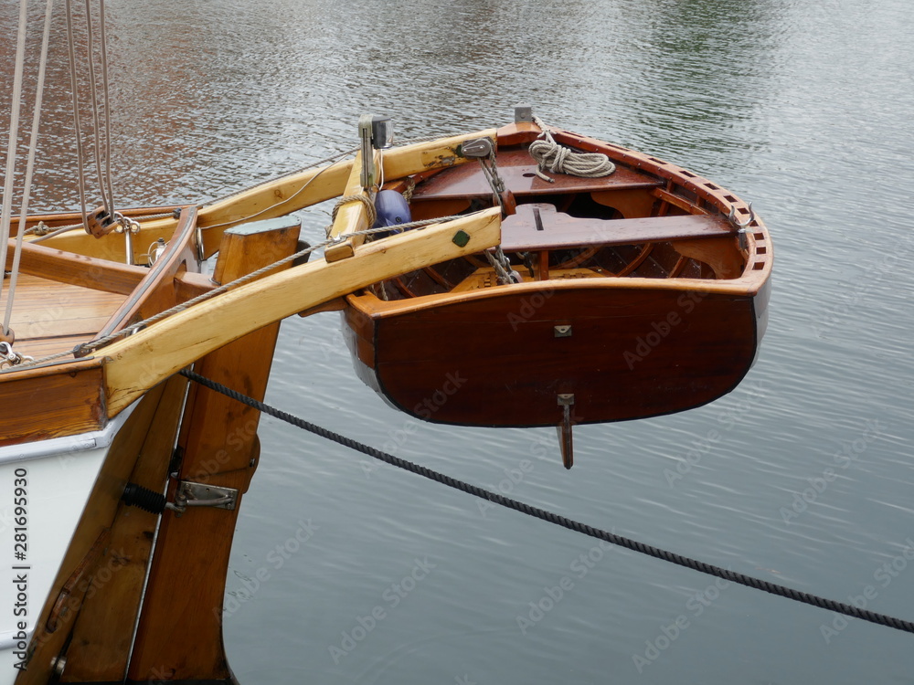 Dinghy, small rowing boat made of mahogany wood, attached to the stern ...