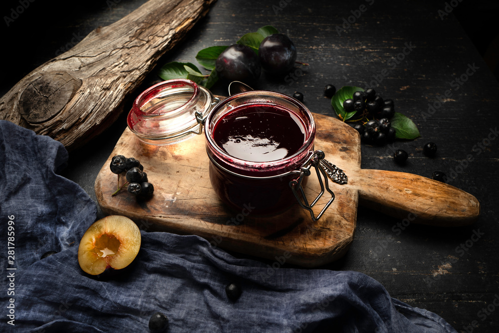 Freshly made plum jam in a jar and garden fruits on a table with ...