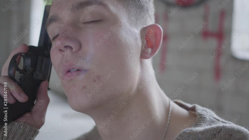 Portrait of guy with a gun standing and smoking cigarette going to ...