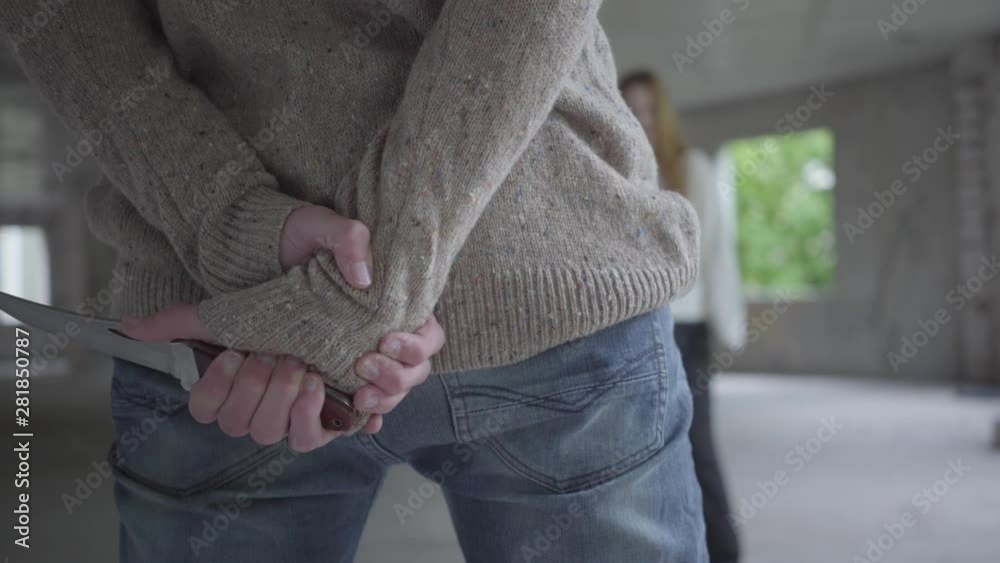 Back view of armed man, holding the knife in his hands, hiding it ...