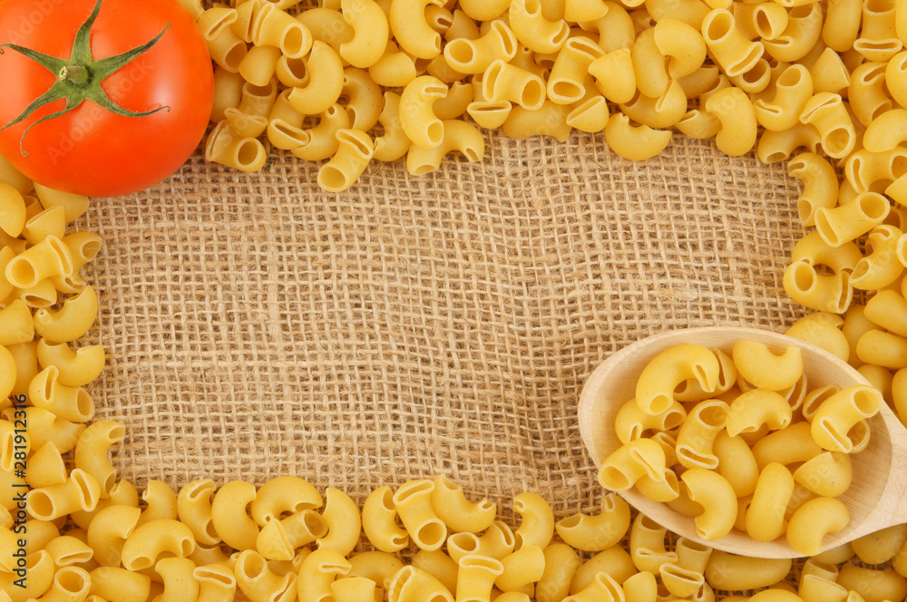 Raw macaroni frame on sack hessian burlap background with spoon and ...