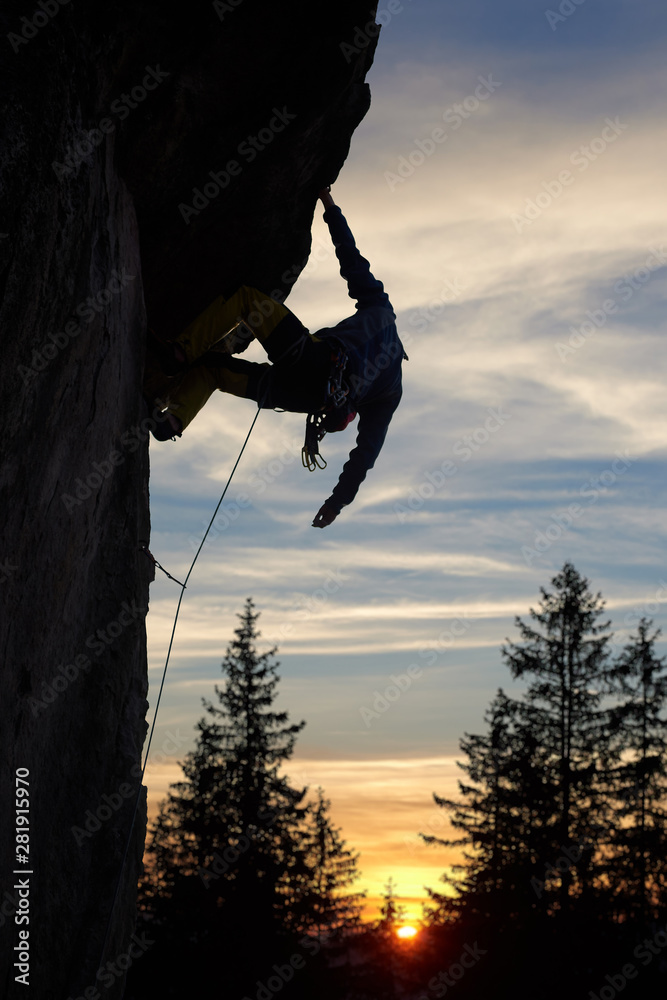 Back view of male climber silhouette hanging on rock. Young man looking ...