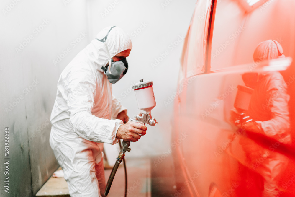 car painter engineer and auto mechanic working and painting a red car ...