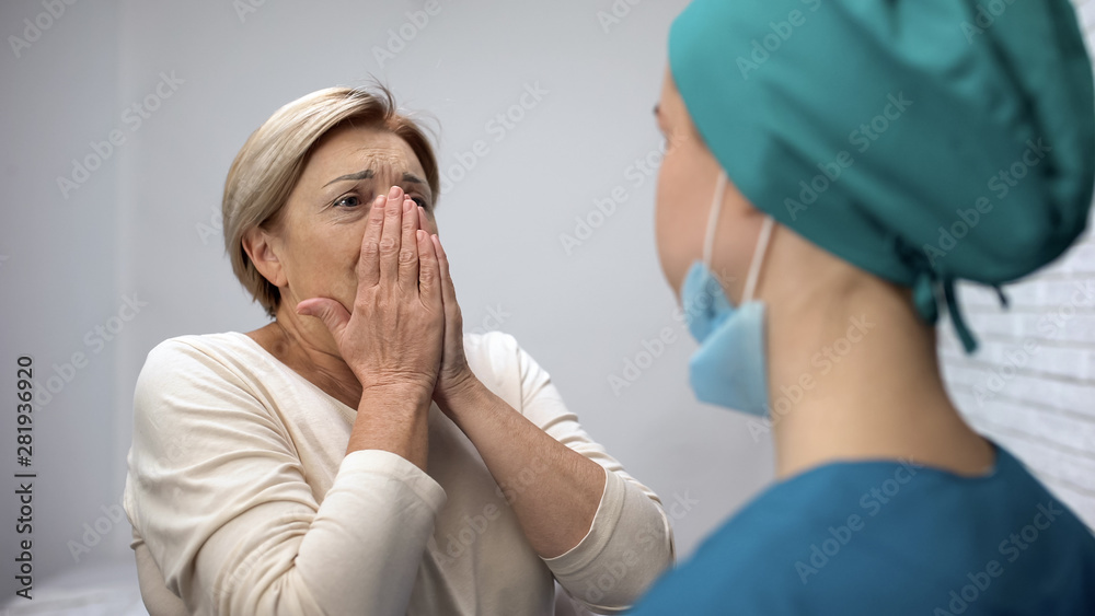 Nurse telling mature patient shocking news, terrified woman crying ...