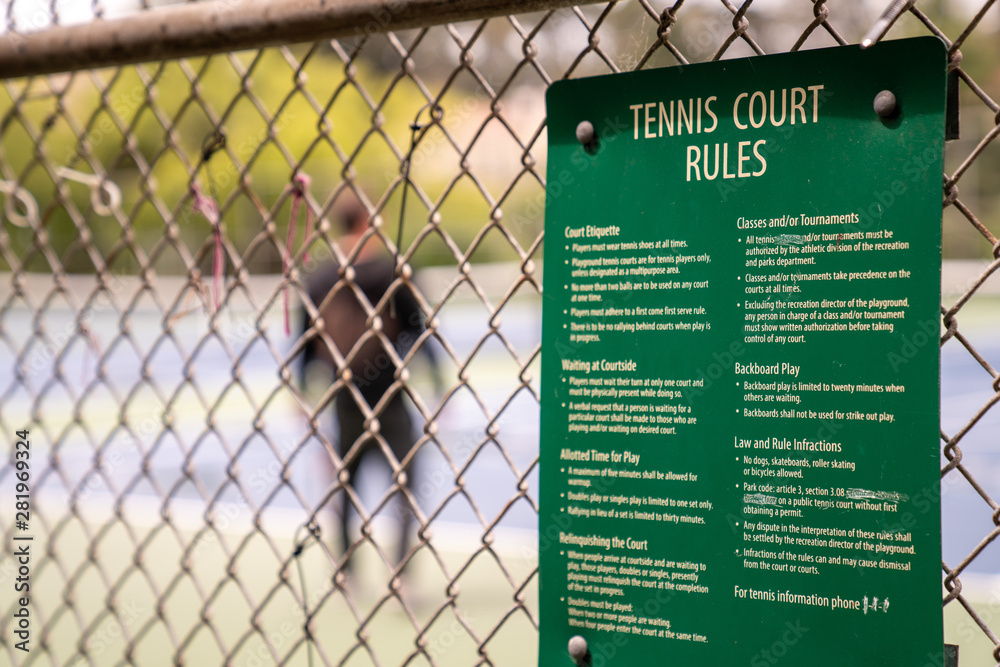 Tennis court rules posted outside of a community tennis court with man ...