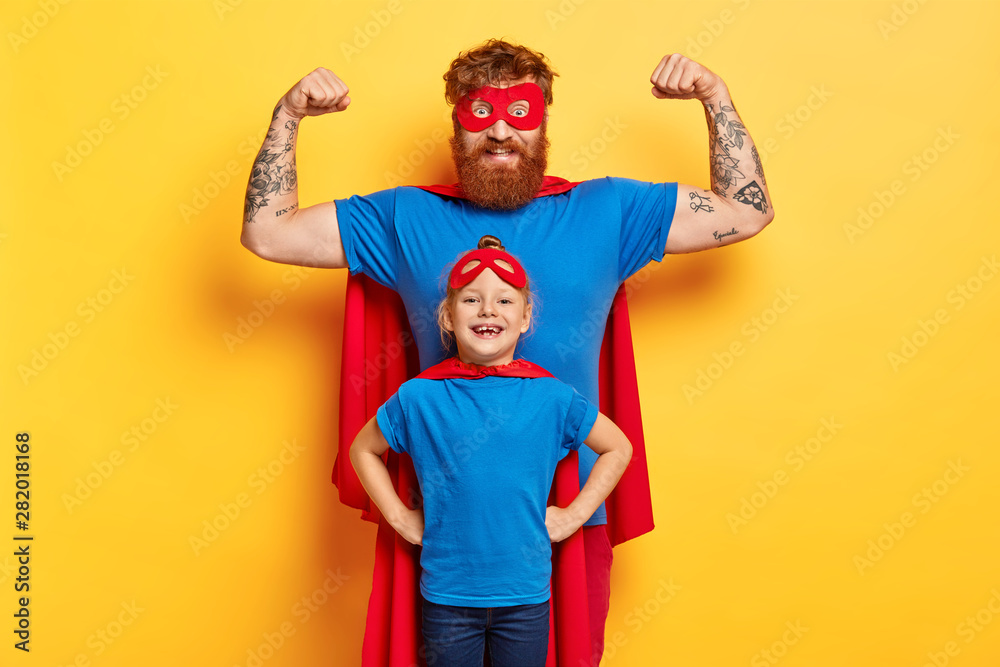 Family fun concept. Joyful strong father raises arms and shows biceps ...