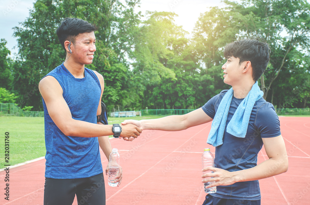 Two friends runners greeting each other handshaking at the stadium ...