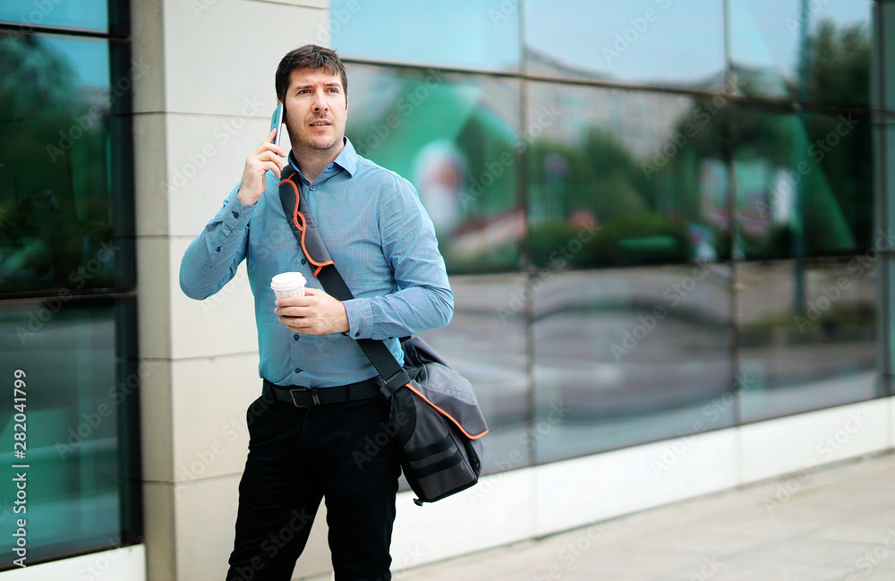 Shot of a handsome commuter taking a phone call while walking outside ...