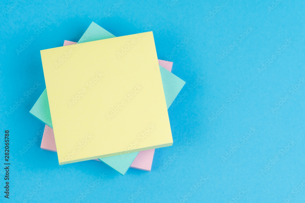 Stack of sticky notes on solid blue background with pink, blue and ...