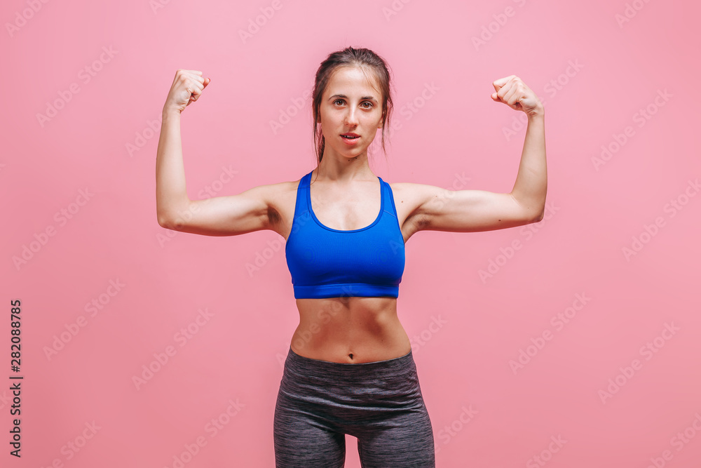 Skinny girl showing biceps on a pink background Stock Photo | Adobe Stock