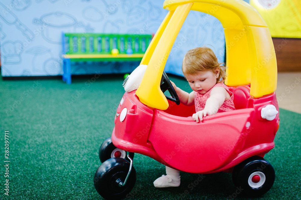 Children, little girl child rides on a red big car on the road. Close ...