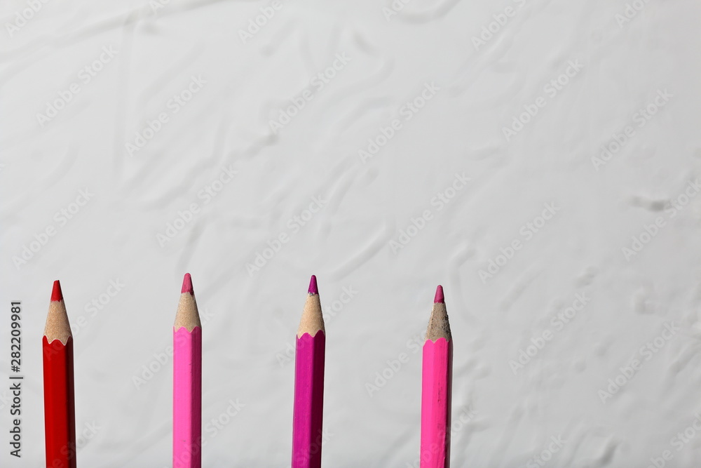 Colored pencils in coral and pink. They are located vertically. Against ...