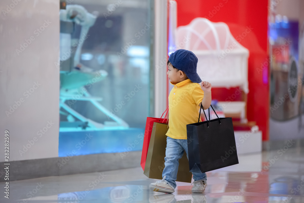 Kid shopping. Asian little boy in yellow shirt and jeans enjoyment of ...