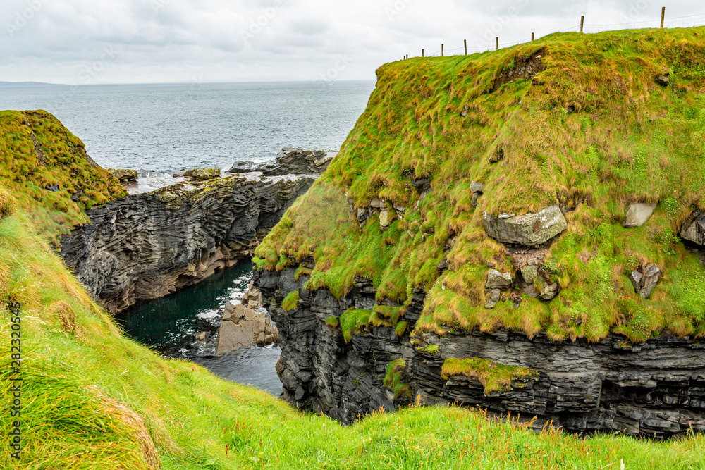 Narrow sea inlet between the hills with green grass in the coastal walk ...