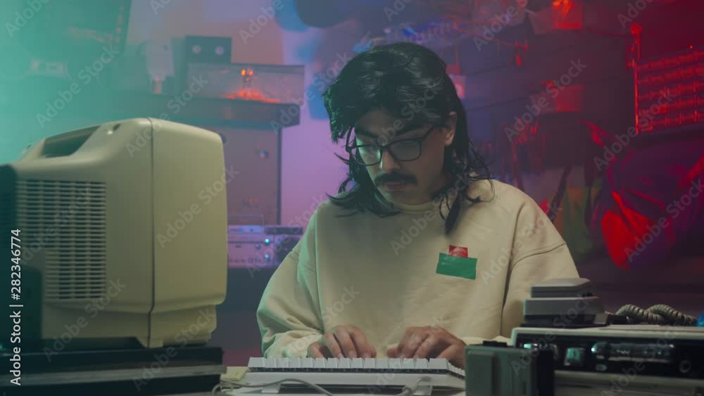In the '80s or '90s young man using his personal computer typing on a ...