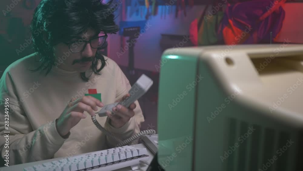 Computer nerd from the '80s or '90s using a telephone to place a call ...