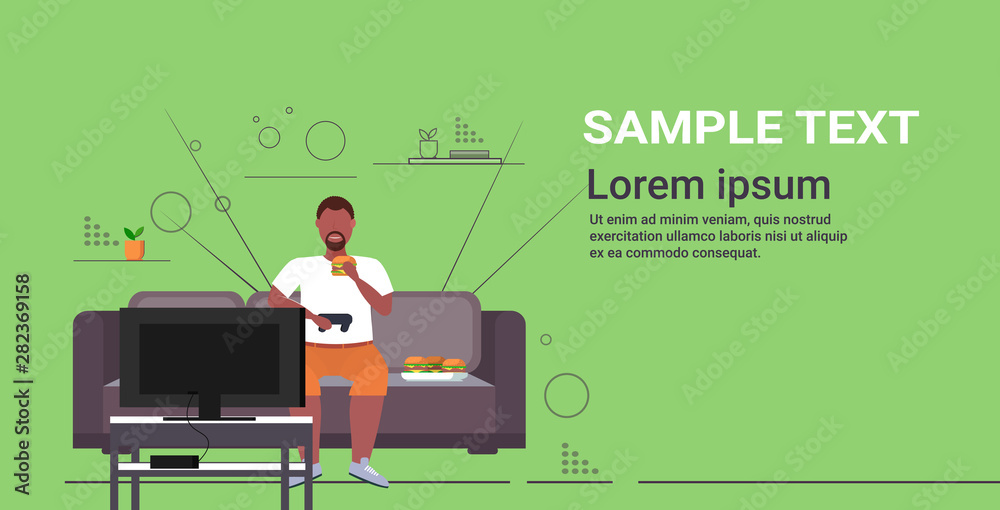 fat obese man sitting on couch eating hamburger using joystick game pad ...