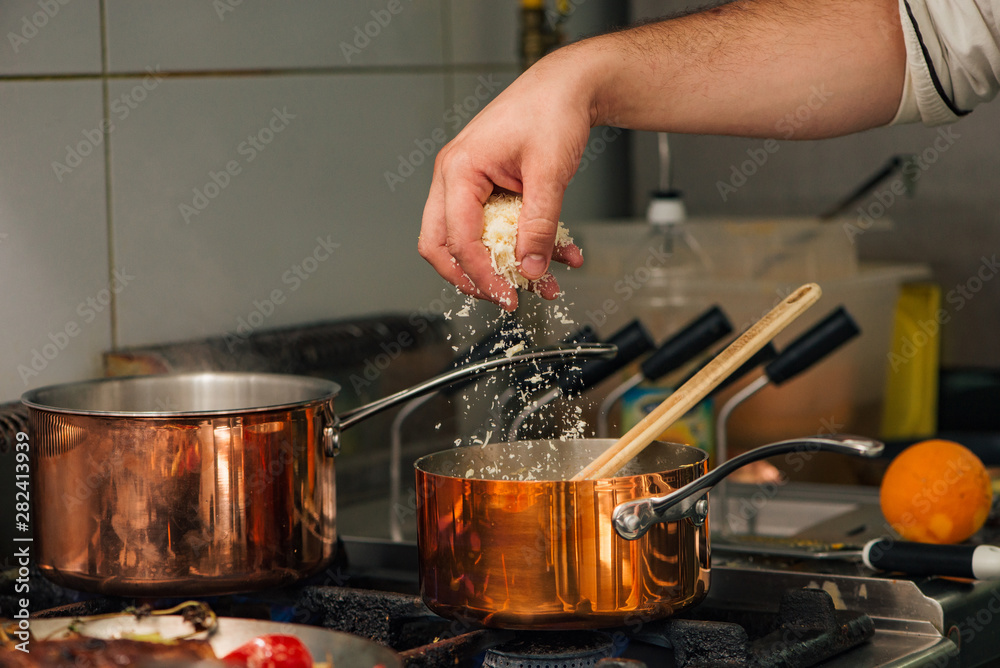 Chef cooking, adding parmesan cheese. Preparing delicious food, close ...