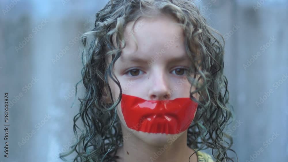 Close up portrait of a curly sad teenager girl with her mouth taped ...