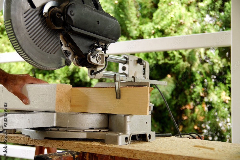 carpenter using a circular saw to cut a wooden beam. Woodworking and ...