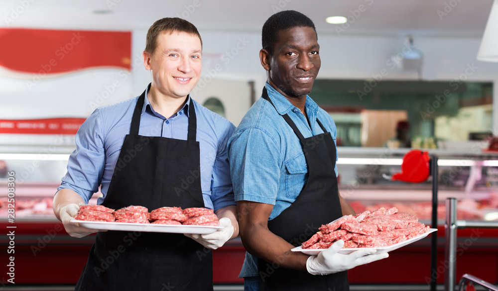 professional butchers standing in butcher shop with trays Stock Photo ...