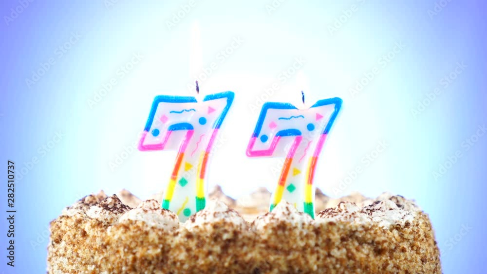 Birthday cake with a burning birthday candle. Number 77. Background ...