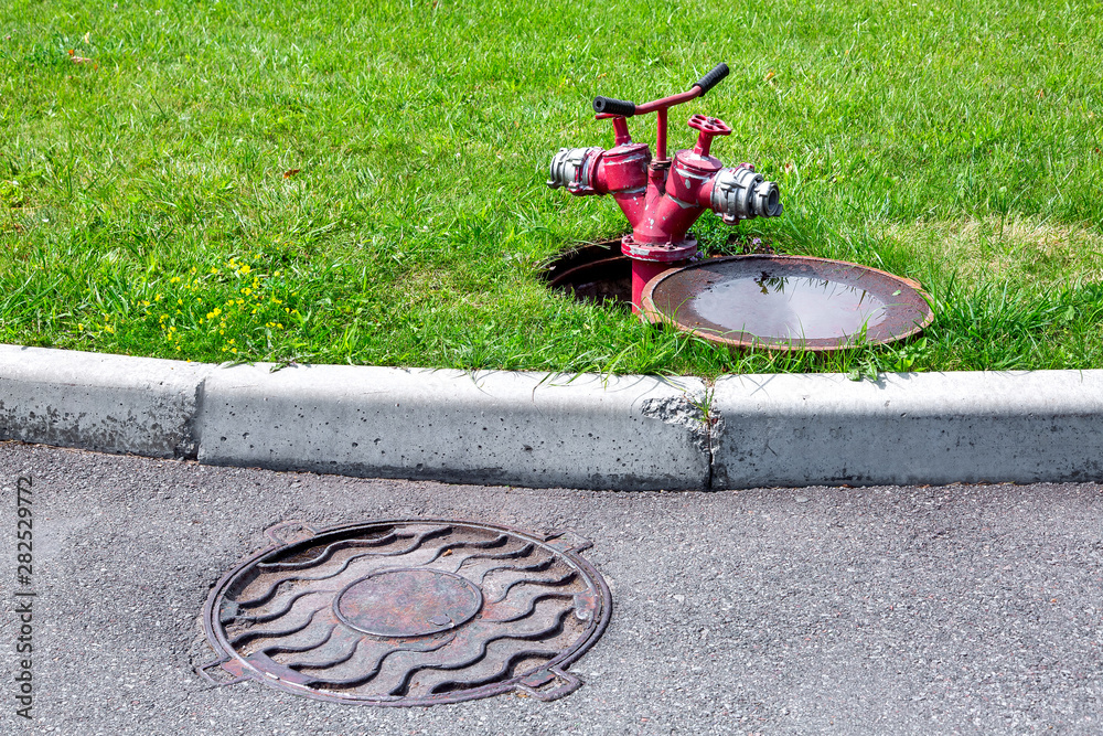 fire hydrant red pipe with a gate connected to an open hatch on a green ...