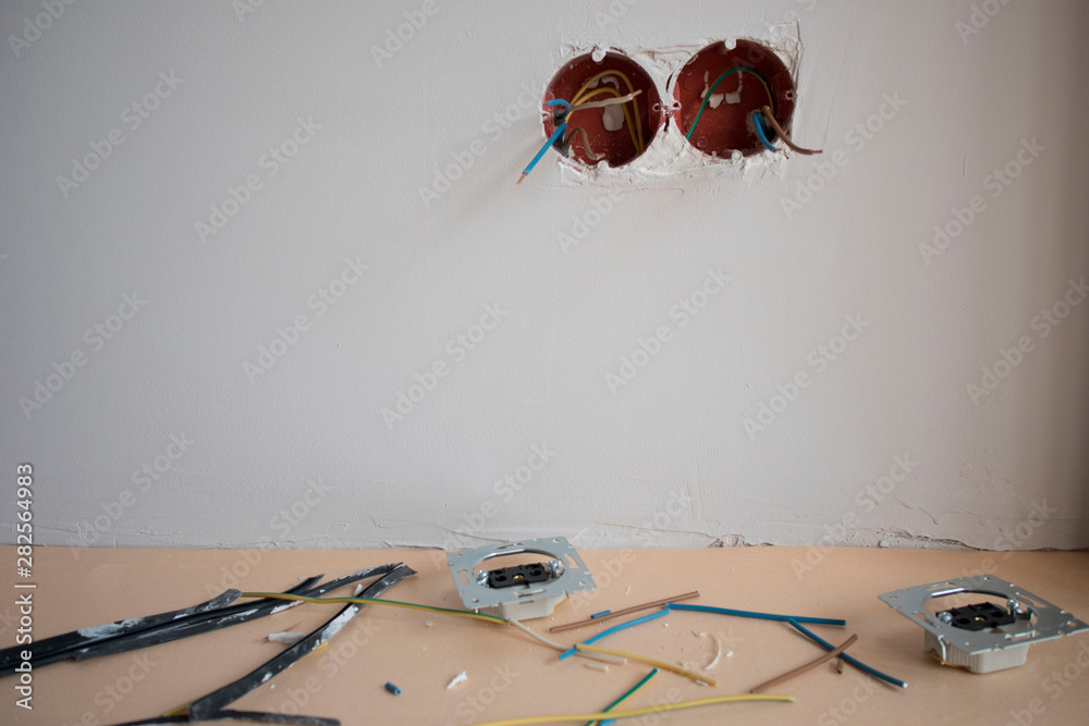 Electrical wires sticking out from electrical socket hole on beige ...