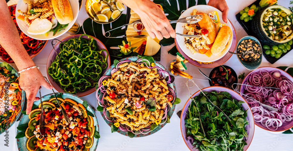 Vertical view of people firends hands taking food from catering table ...