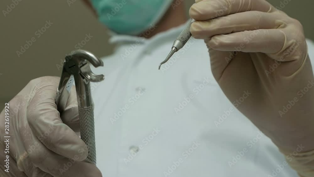 close-up of a dentist holding a tooth extraction tool dentistry sterile ...