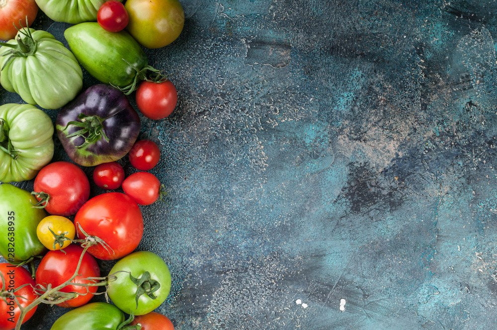 Different types, colors and shapes of tomatoes on a blue concrete ...
