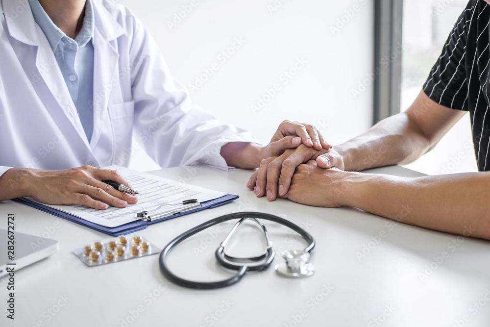 Doctor touching patient hand for encouragement and empathy in the ...