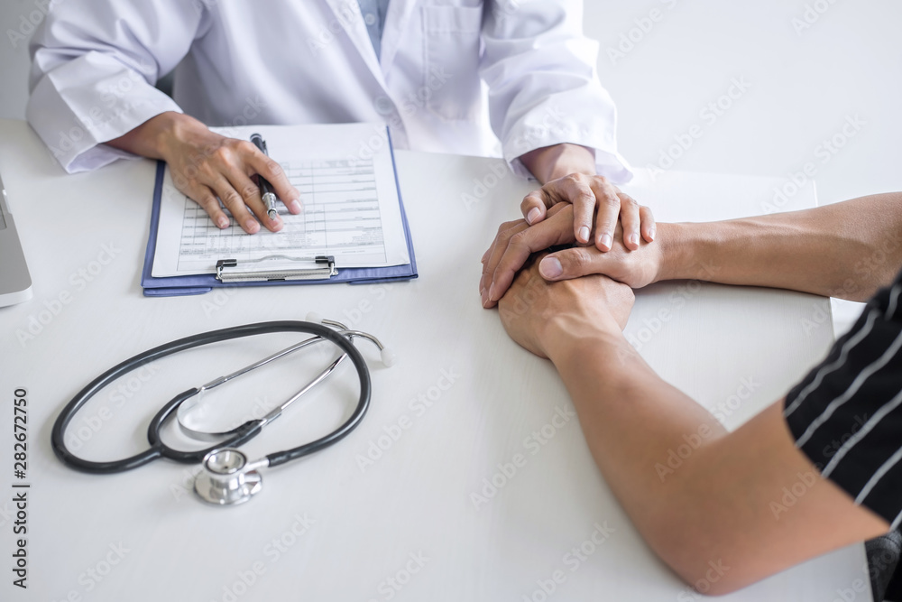 Doctor touching patient hand for encouragement and empathy in the ...