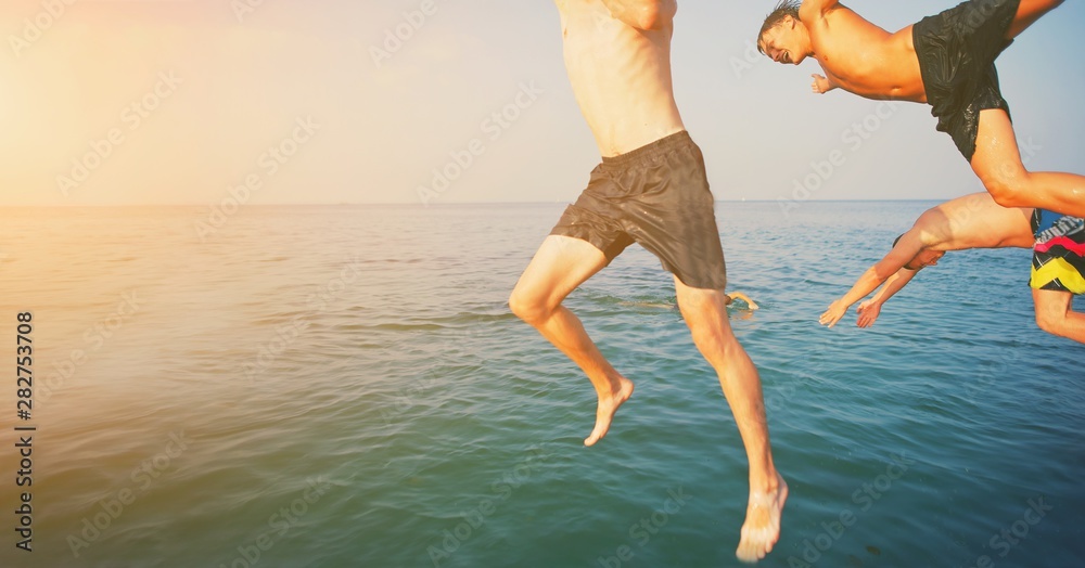 Group of happy crazy people having fun jumping in the sea water from ...