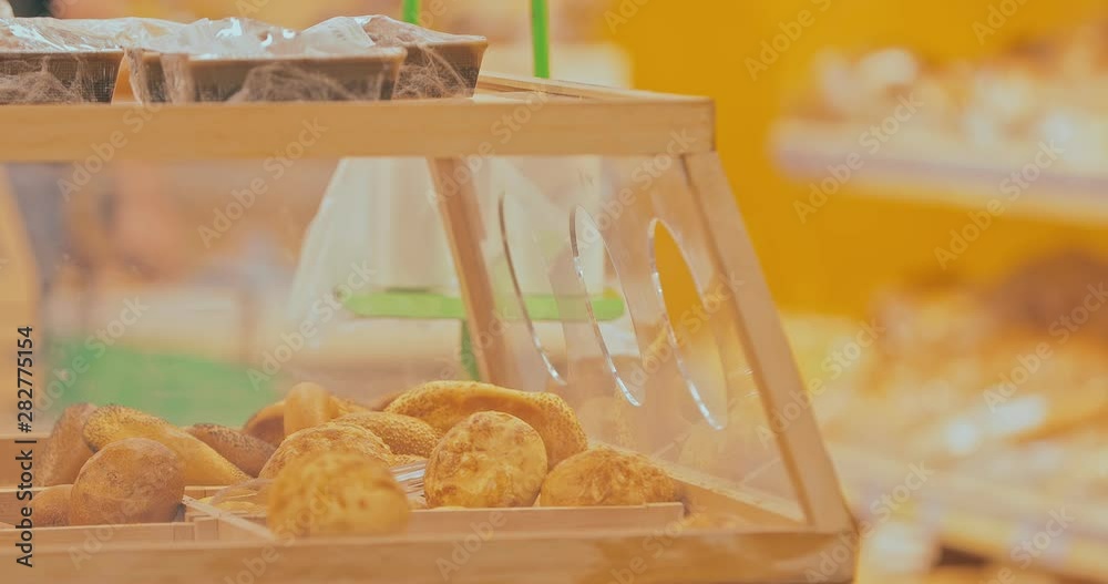 Buns in a shop window of a bread department of a supermarket. Man takes ...