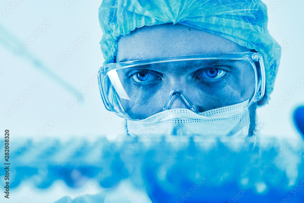 Scientist dropping liquid with pipette into cells Stock Photo | Adobe Stock