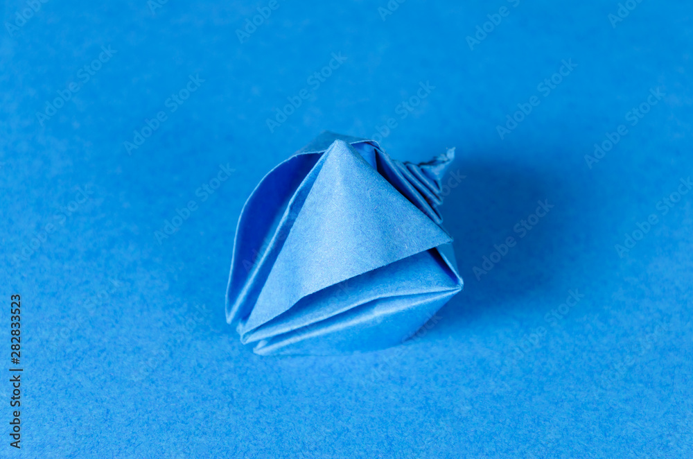 Blue origami seashell on blue background. Japanese art of paper folding ...