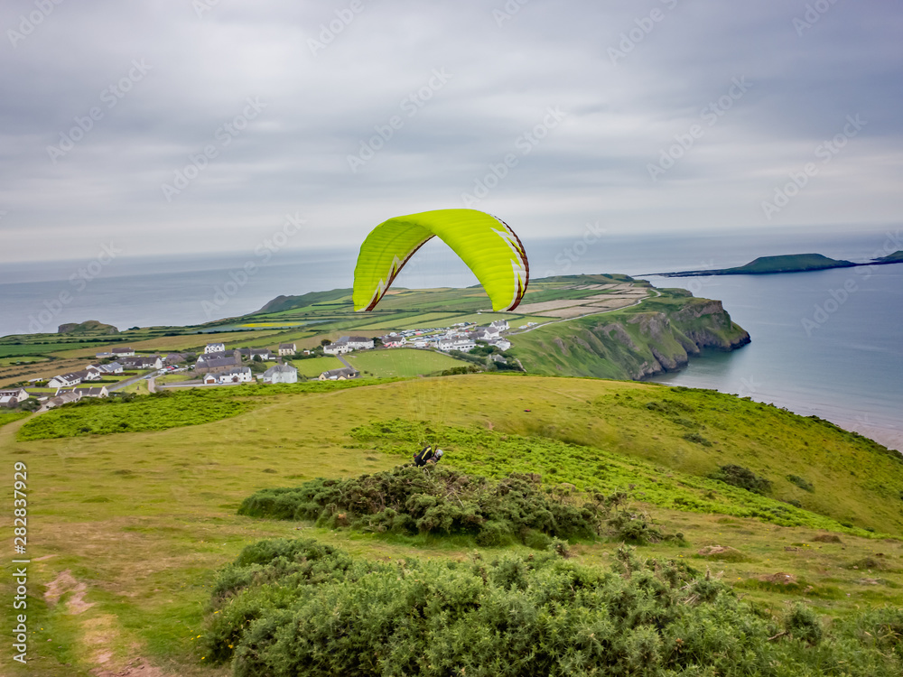 Paraglider on the cliff top of the Gower Way above Rhossili Bay taking ...