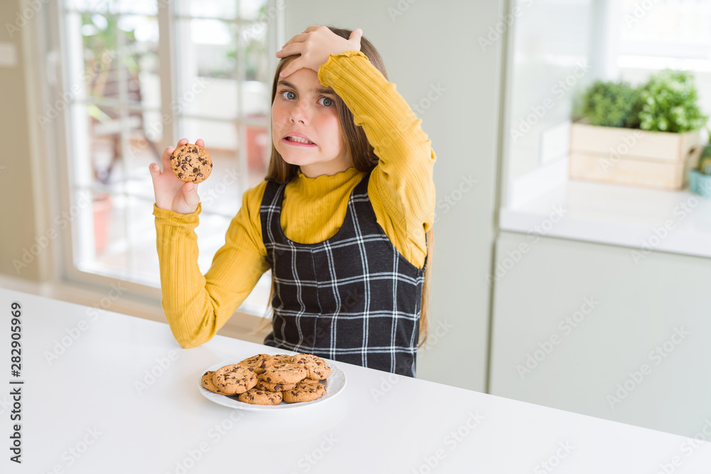 Beautiful young girl kid eating chocolate chips cookies stressed with ...