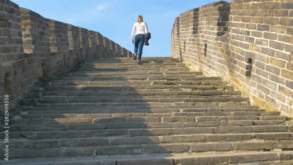 LOW ANGLE: Woman walks up a flight of stairs on top of the Great Wall ...