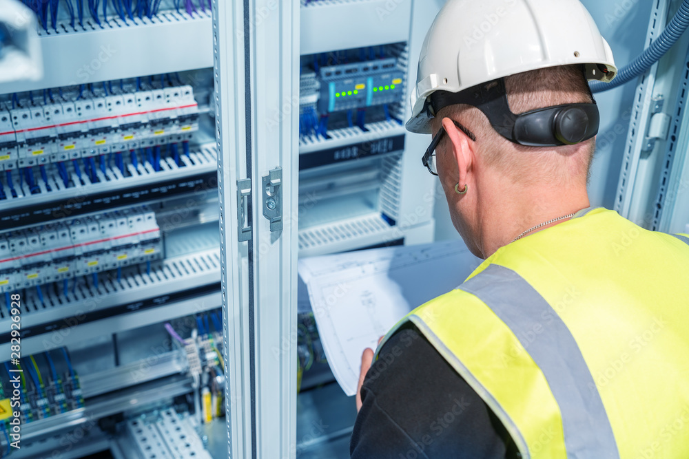 an electrical engineer reads a wiring diagram in a control cabinet ...