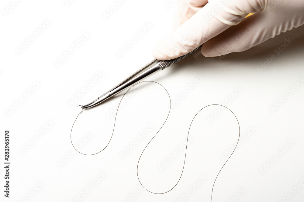 Doctor holding needle holder on white background. Suture thread. Nylon ...
