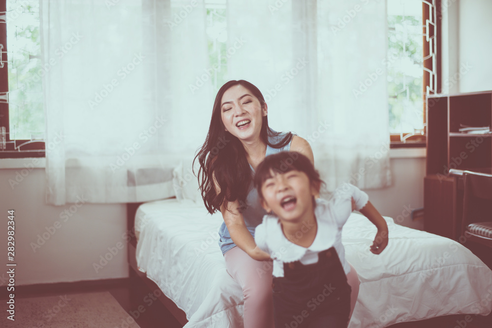 Asian single mom and carrying her cheerful daughter at home together ...