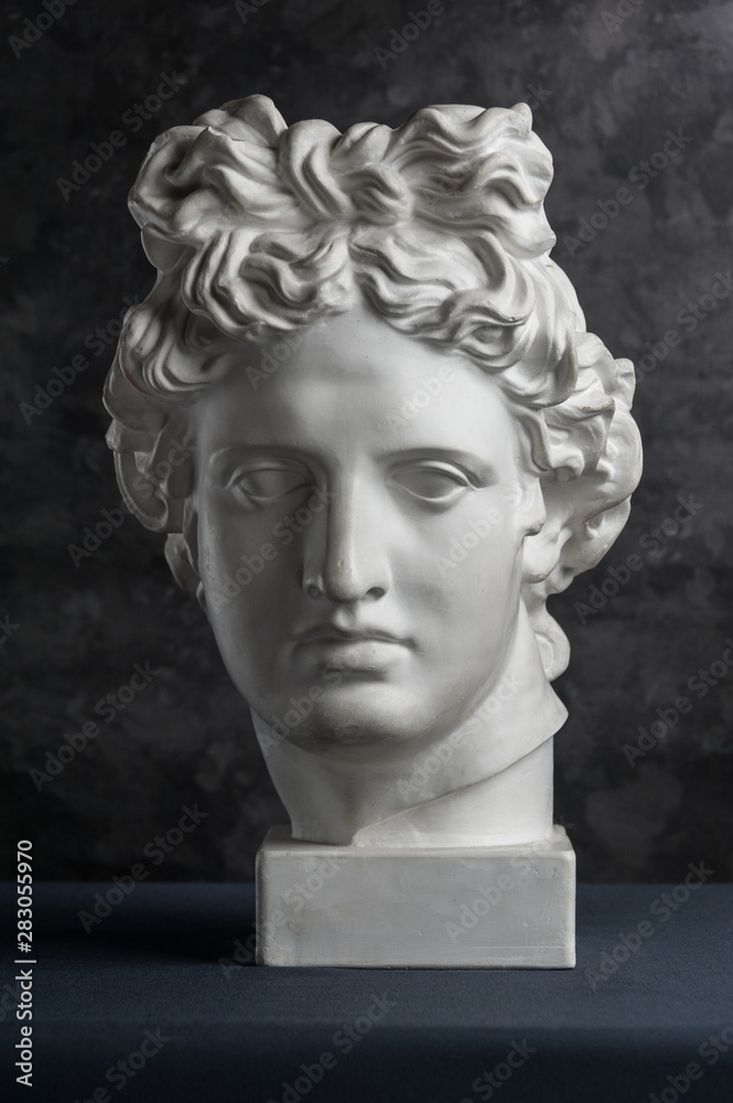 Gypsum copy of ancient statue Apollo head on dark textured background ...