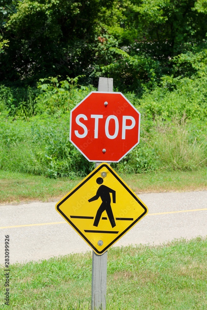 The red stop sign and the yellow crosswalk sign. Stock Photo | Adobe Stock