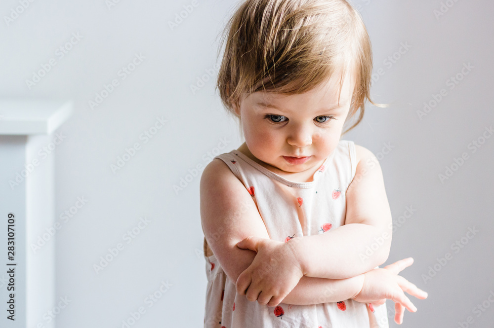 Sad toddler baby girl looking down with her arms crossed Stock Photo ...